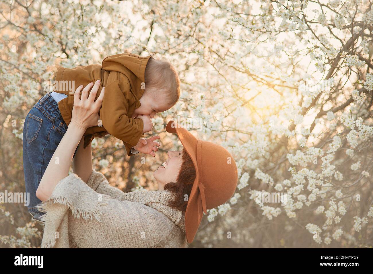 Mom holds the baby against the background of flowering trees Stock ...