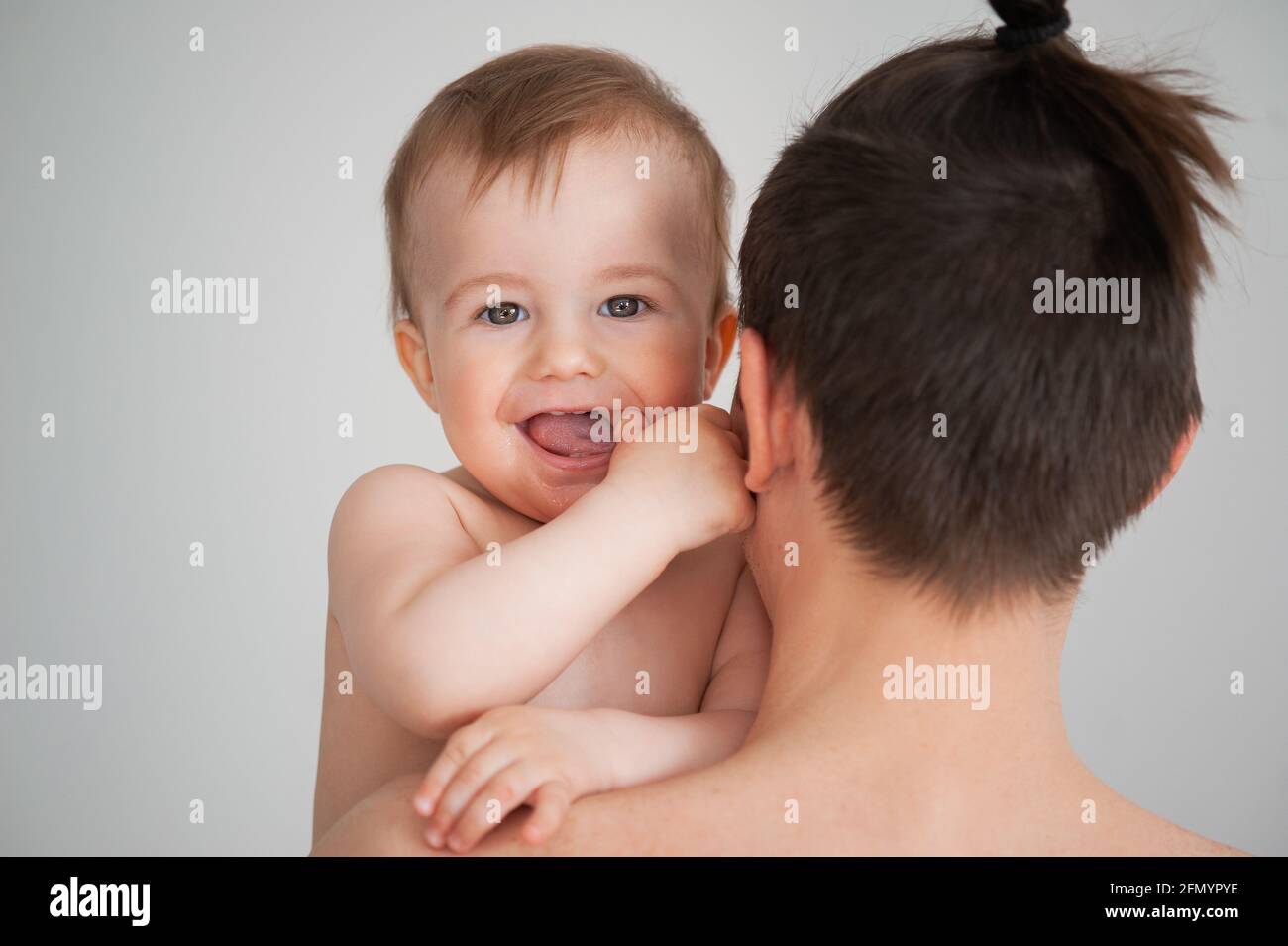 father holding a cute little smiling baby in his arms on a white ...
