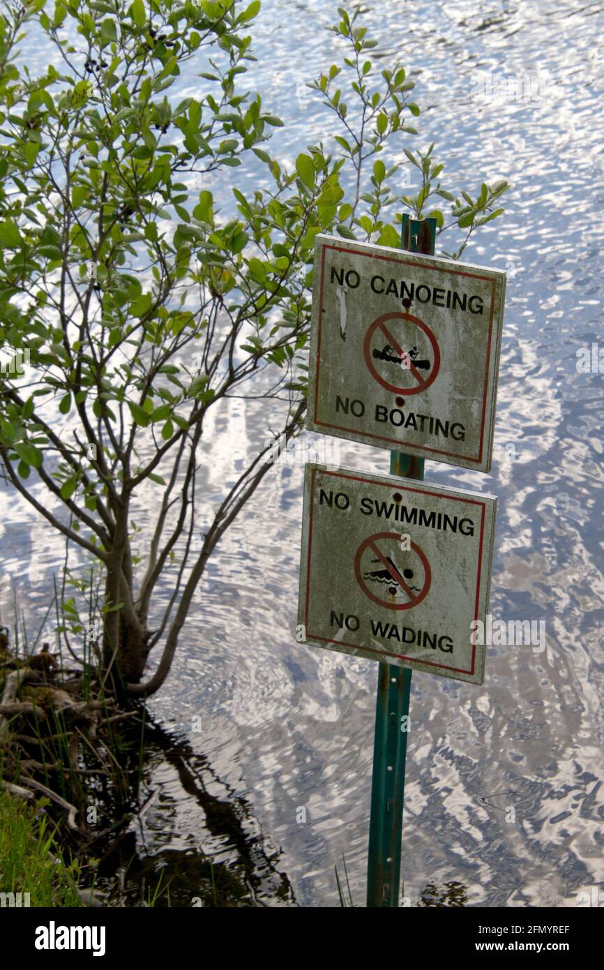 Signs by the side of a lake saying "NO CANOEING, NO BOATING, NO ...