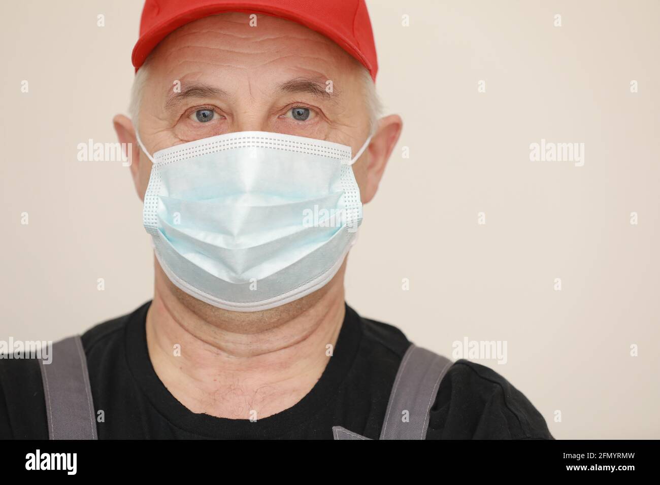 Work are done. Portrait of worker man with medical mask in red overall ...