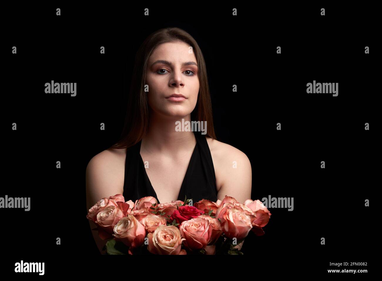 Teenage girl holding bunch of pink roses on black background isolated ...