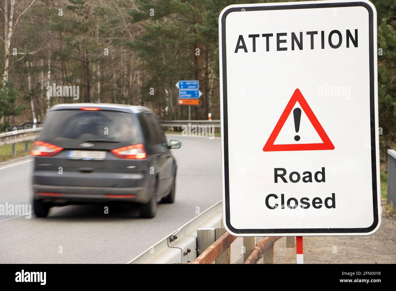 A road sign beside road with riding cars show warning message Road ...