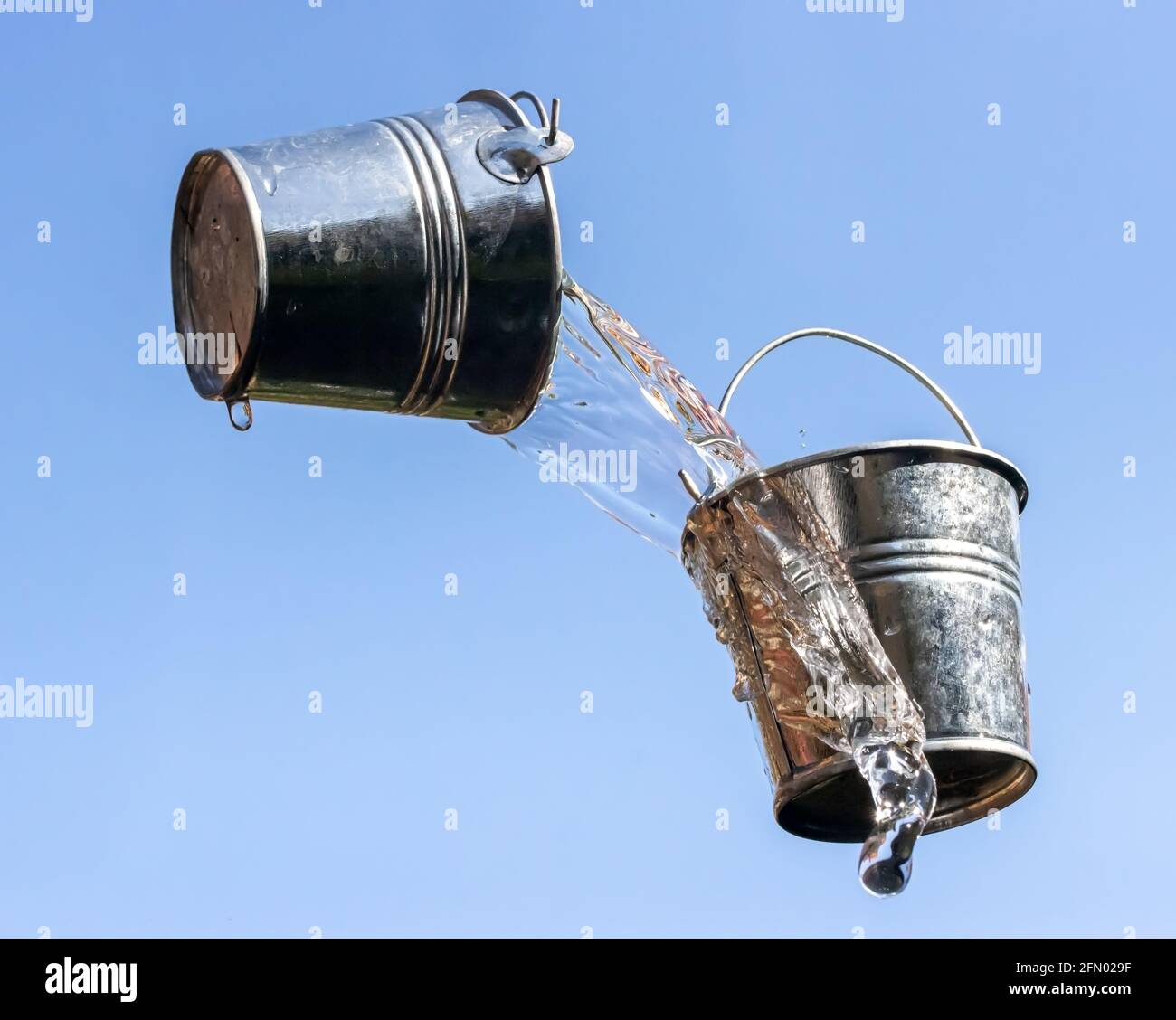 A pouring water from falling bucket to bucket, on a background of blue ...