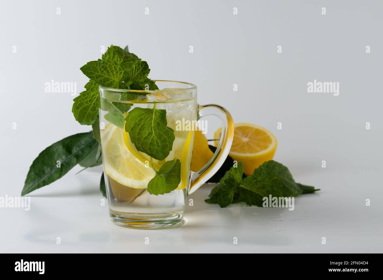 A glass glass of lemonade. Water with lemon slices, mint leaves and ice ...