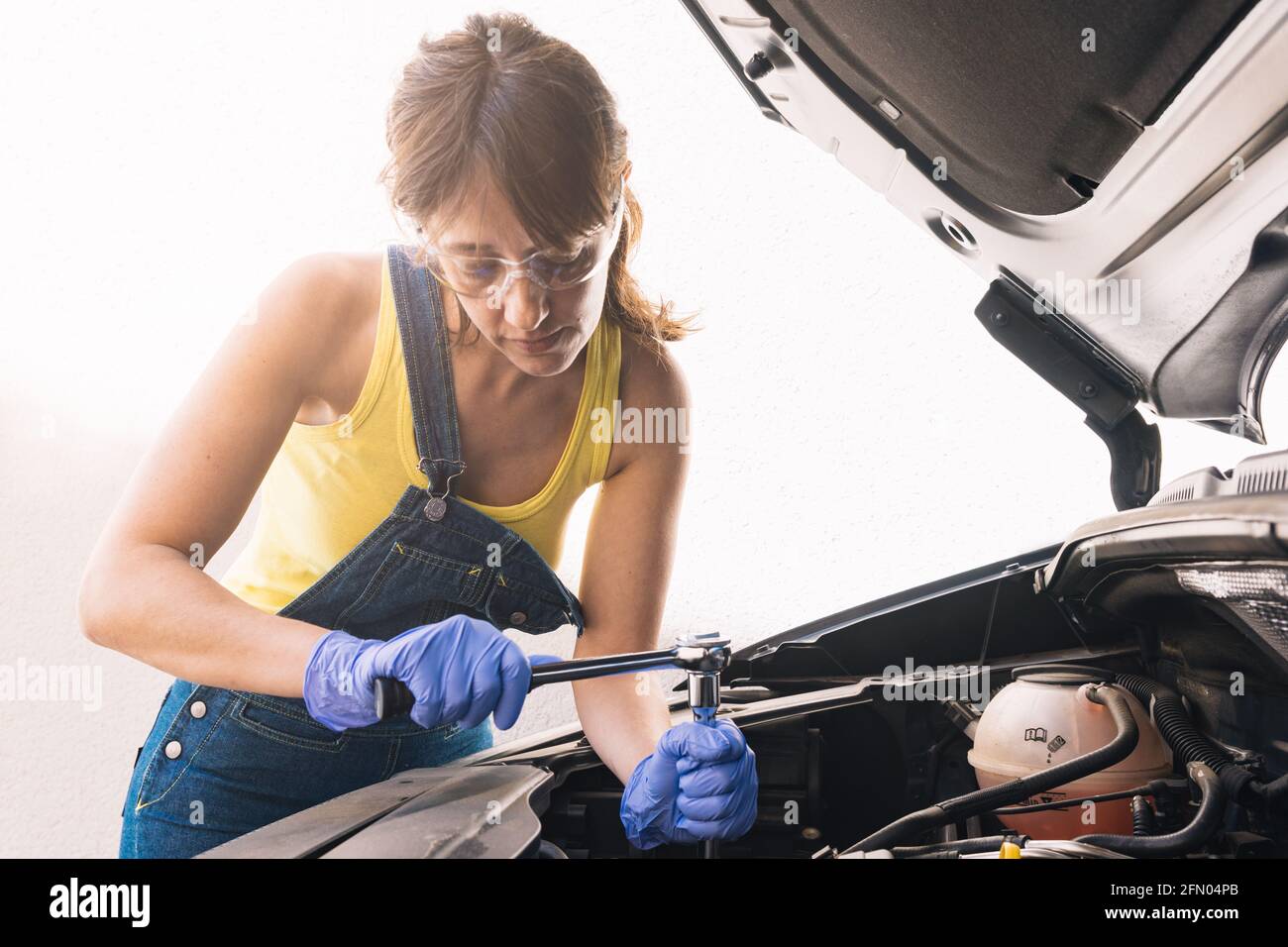 young brunette girl mechanic with goggles yellow t-shirt and blue jean ...
