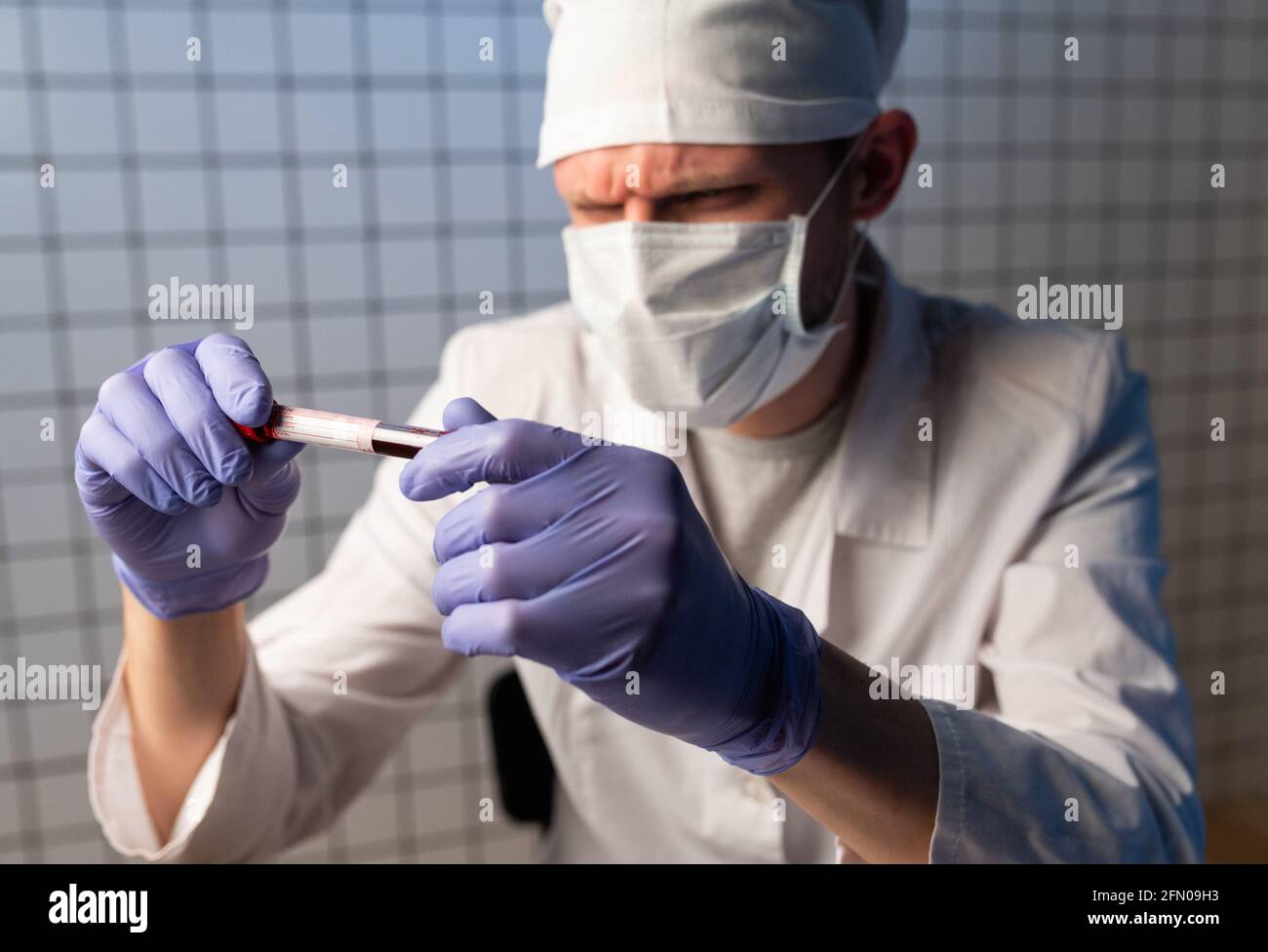 hands of a lab technician with a tube of blood sample and a rack with ...