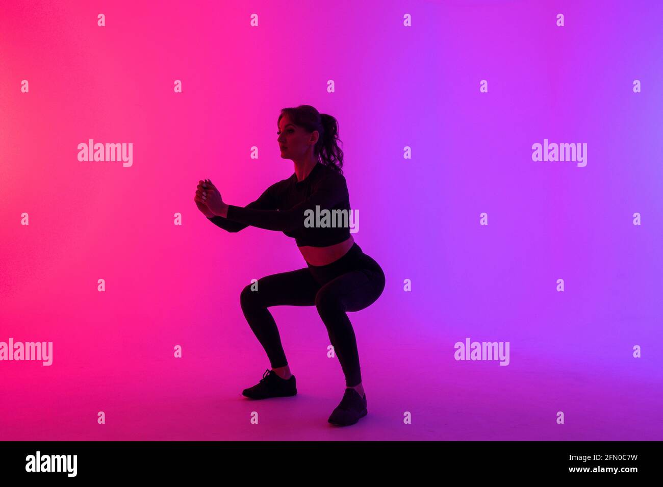 Full length portrait of a young fitness woman doing squatting isolated ...