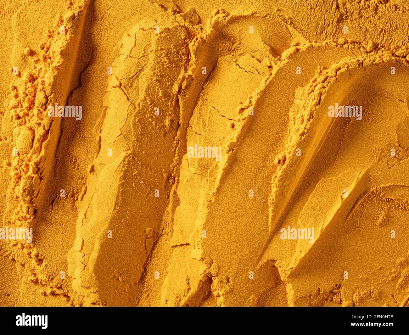 Yellow powder of grated turmeric with texture, food background. View ...
