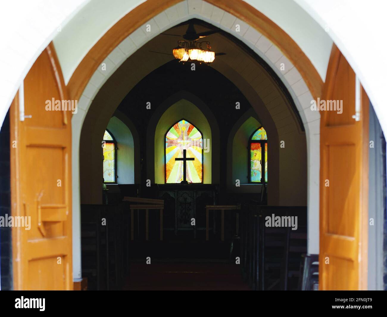 Dark church with light shining through colorful stained glass window ...