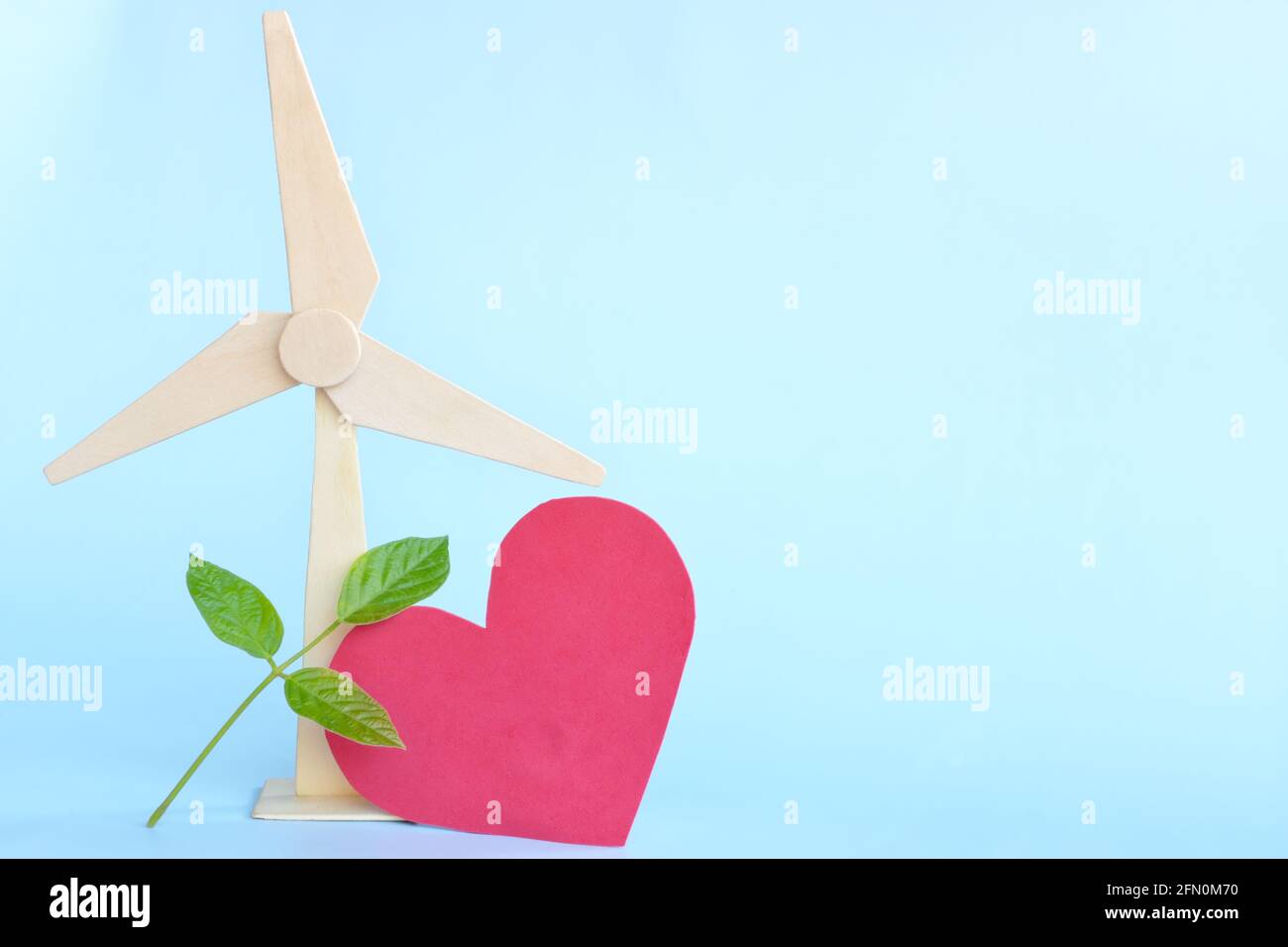 Wooden wind turbine model with fresh green leaves and red heart shape ...