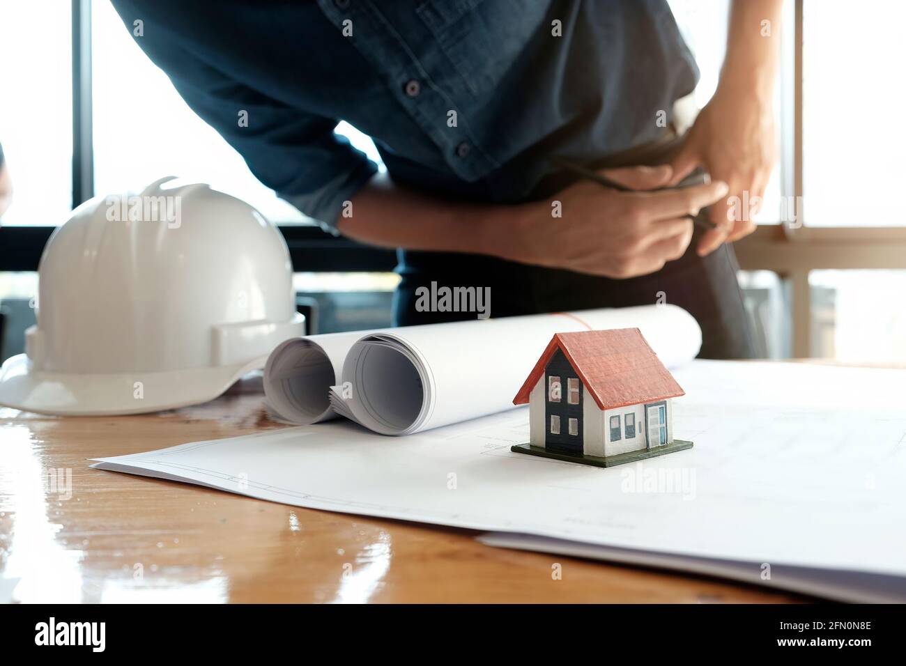 Engineer sketching a building project design with mockup house model ...