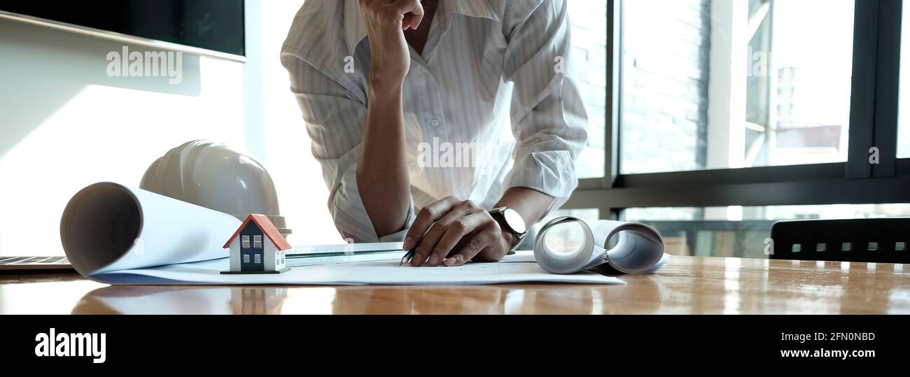 Engineer sketching a building project design with mockup house model ...