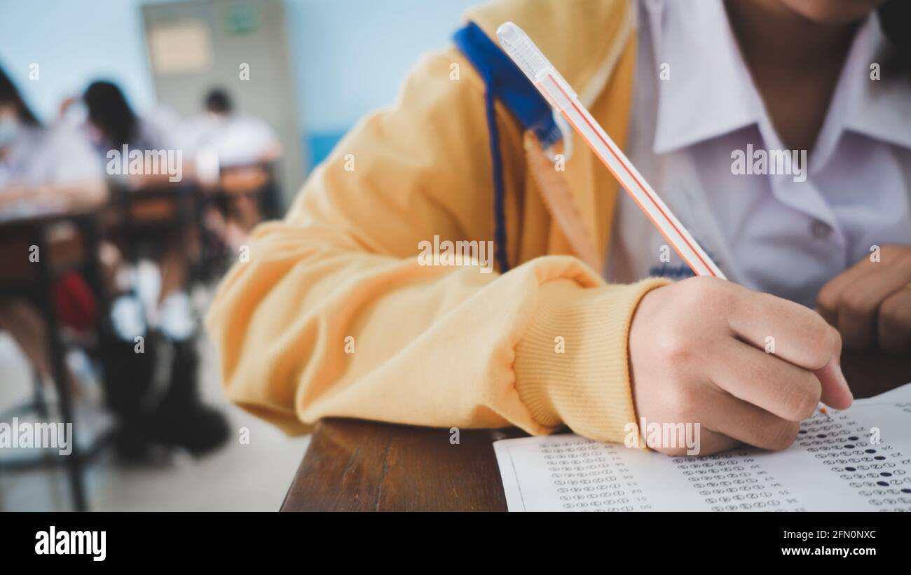 Students writing and reading exam answer sheets exercises in classroom ...
