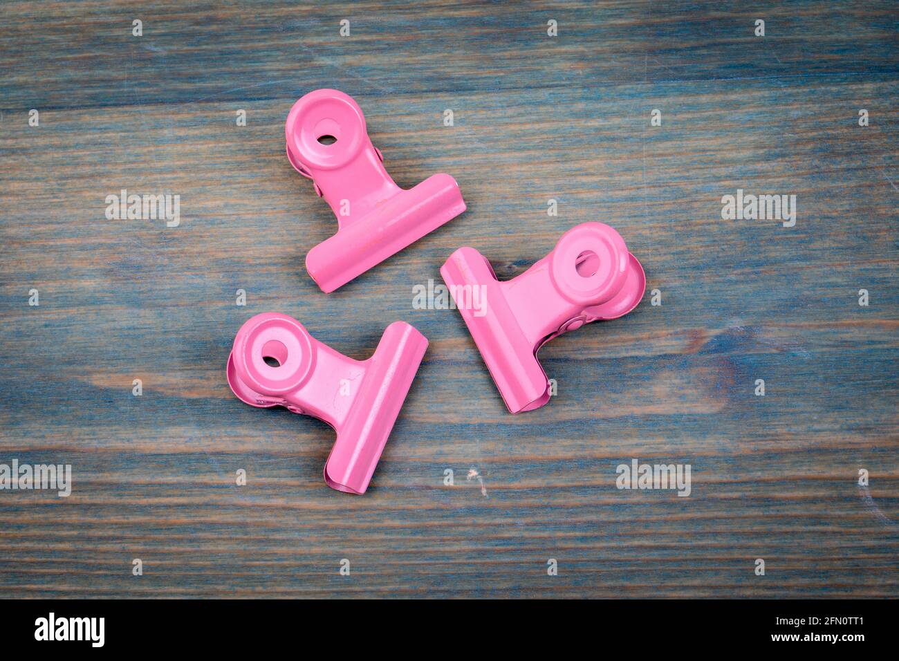 Pink metal paper clip on a painted wooden green texture background ...
