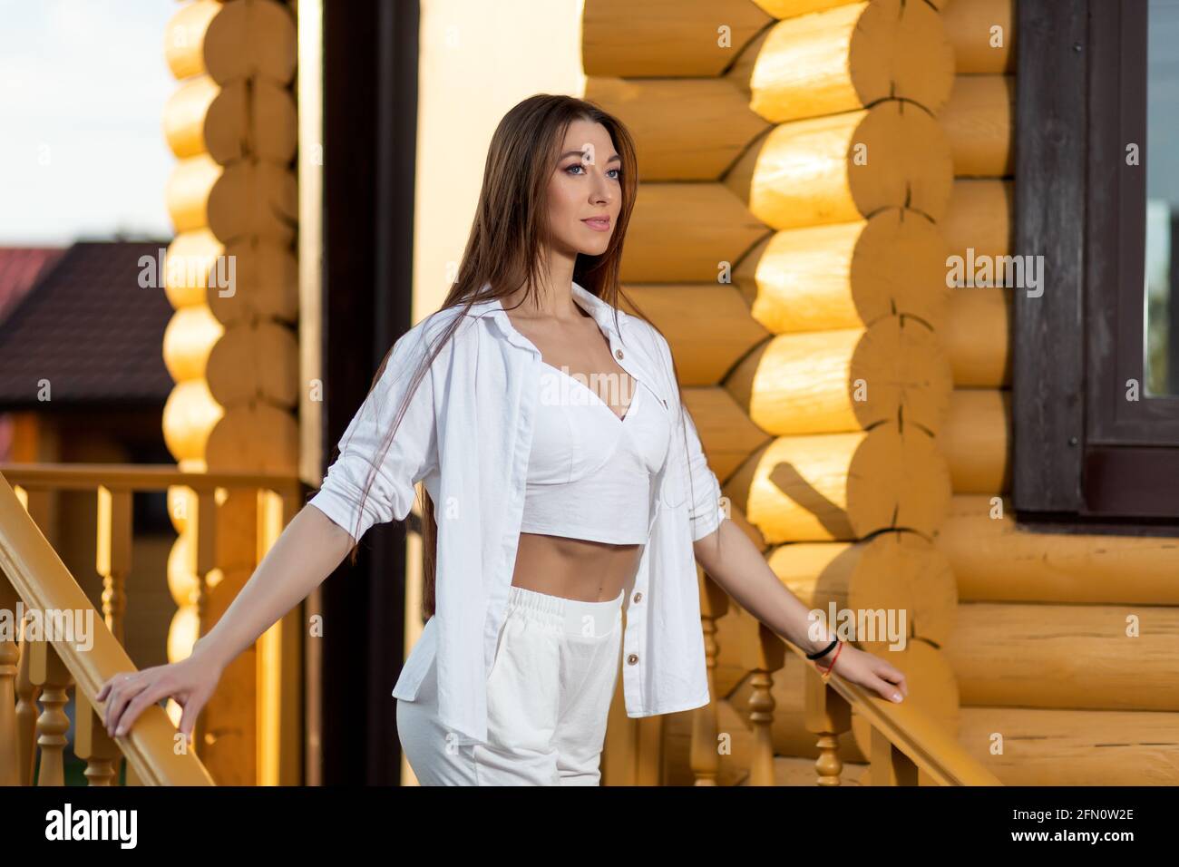 A young woman hostess in white clothes meets guests in her country ...