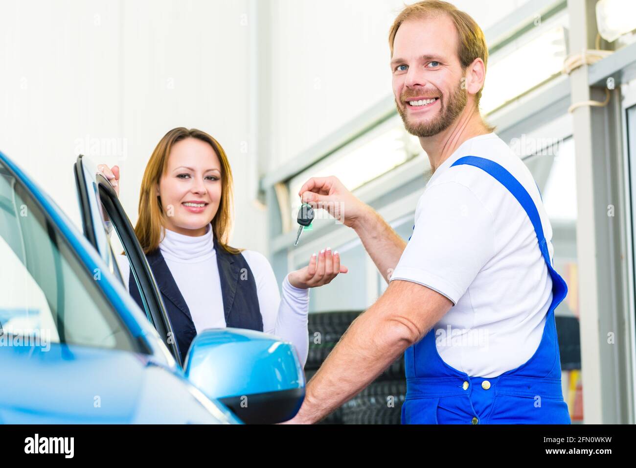 Female client and mechanic in auto workshop or MOT with car for service ...