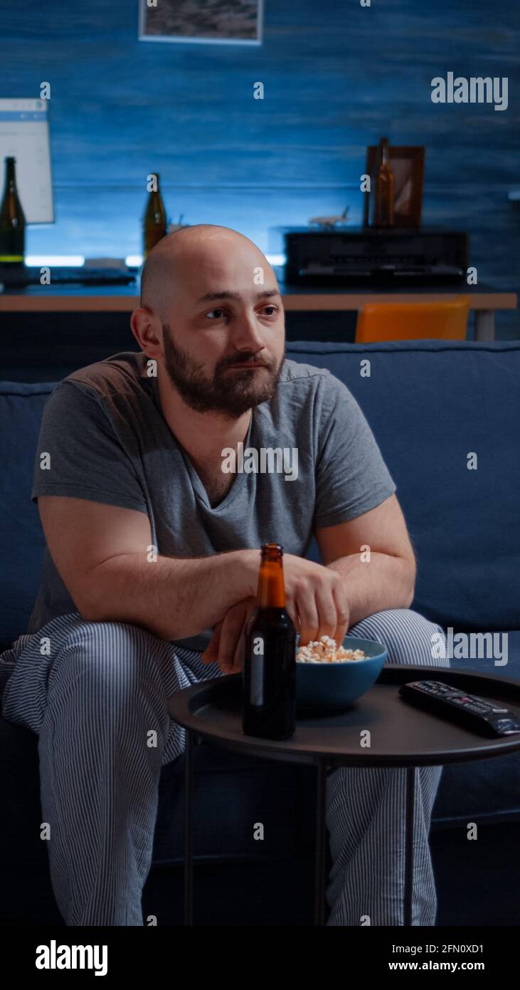 Scared shocked astonished man looking at horror movie at tv, eating ...