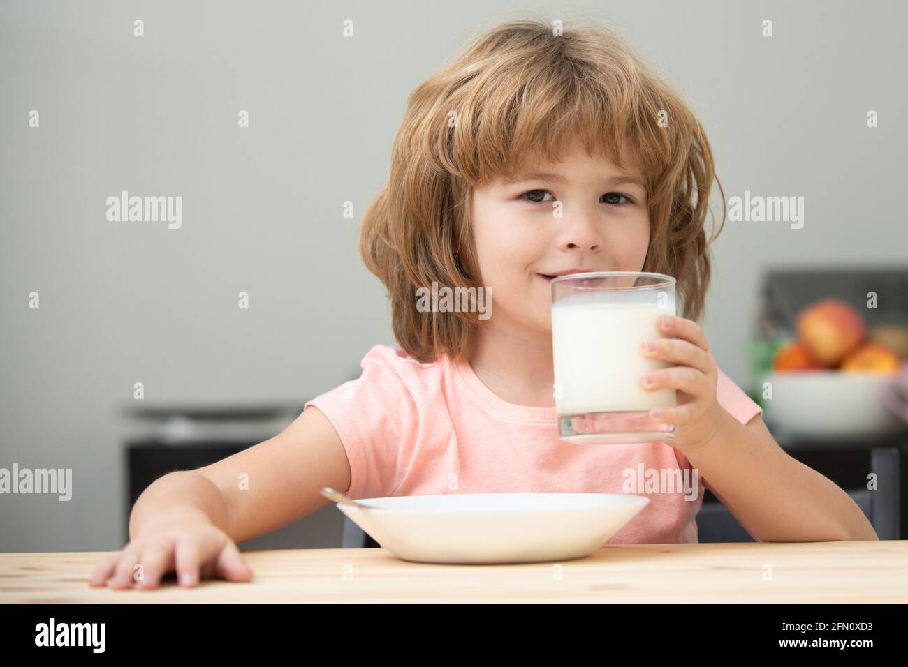Cute little child with glass of milk at table in kitchen. Kid eating ...