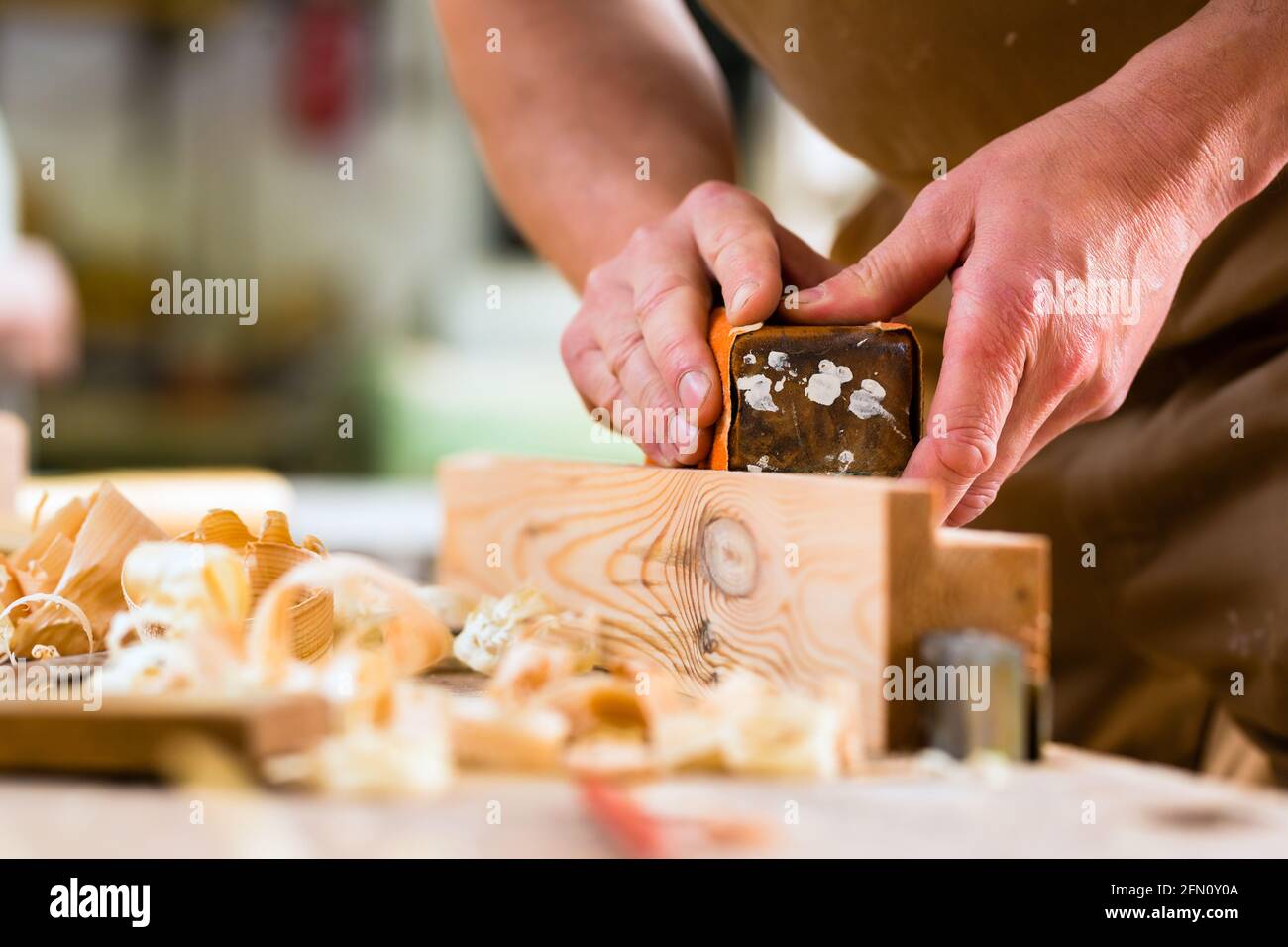 Carpenter working with a sanding block and sandpaper in his workshop ...