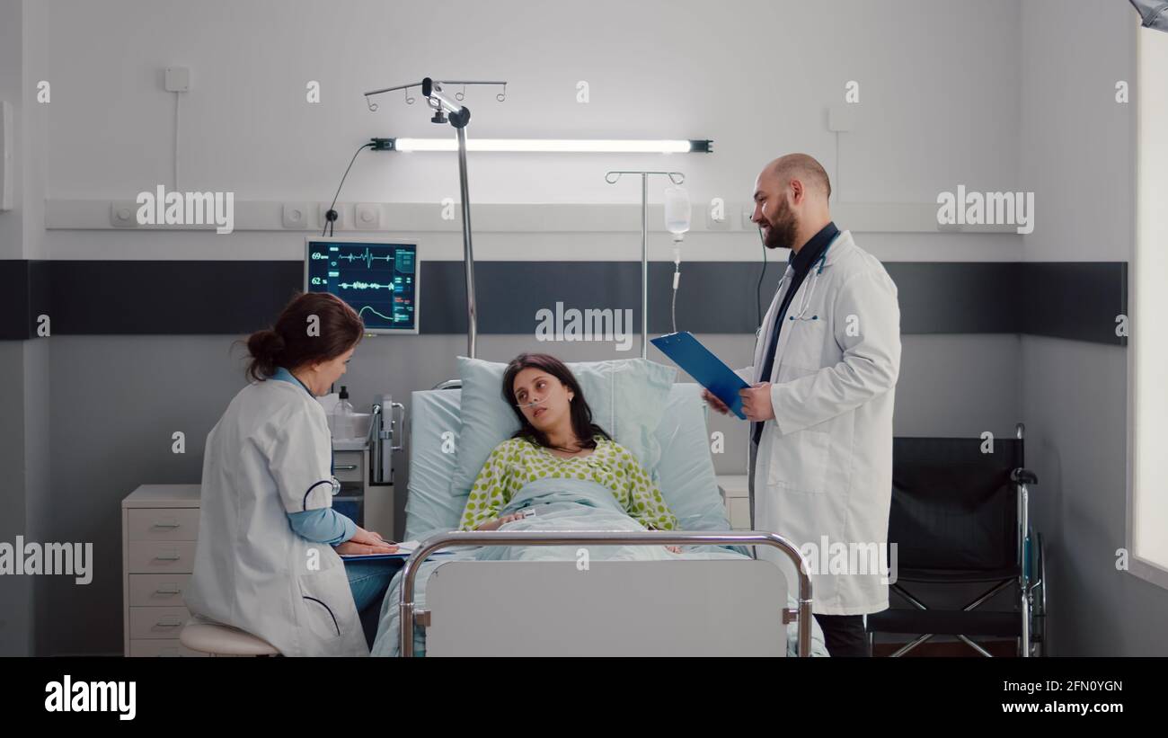 Specialist doctors monitoring sick woman discussing sickness treatment ...