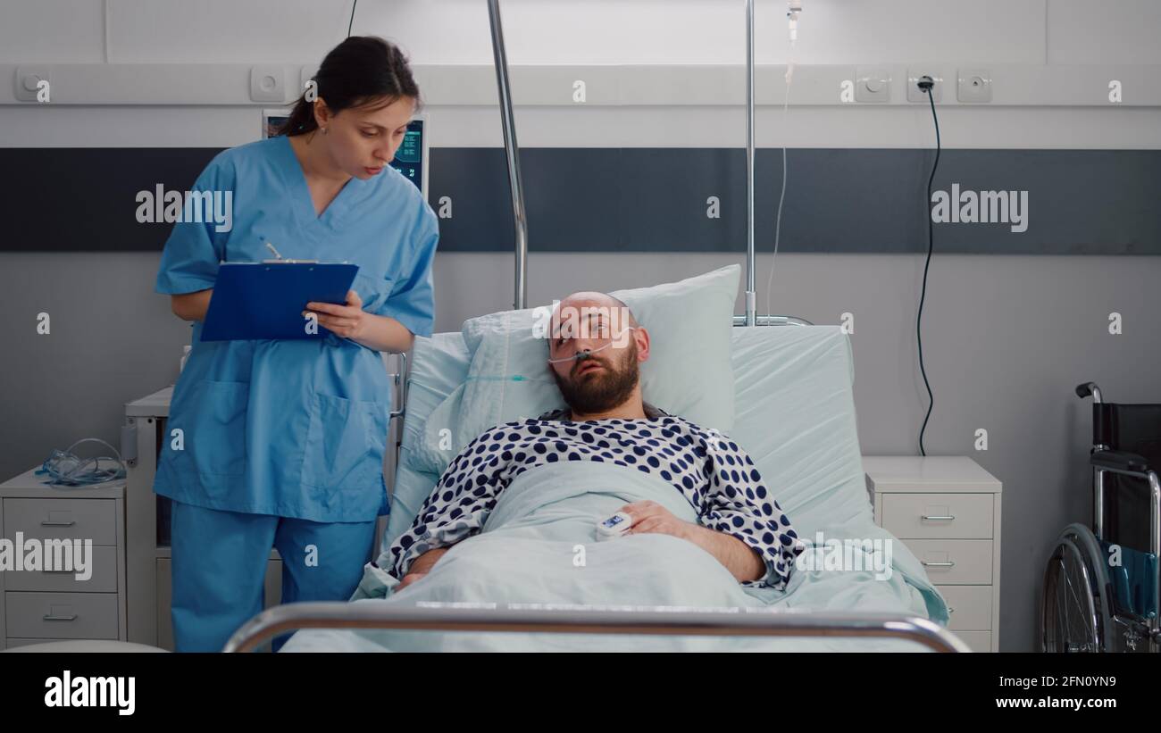 Practitioner nurse monitoring patient during sickness recovery writing ...