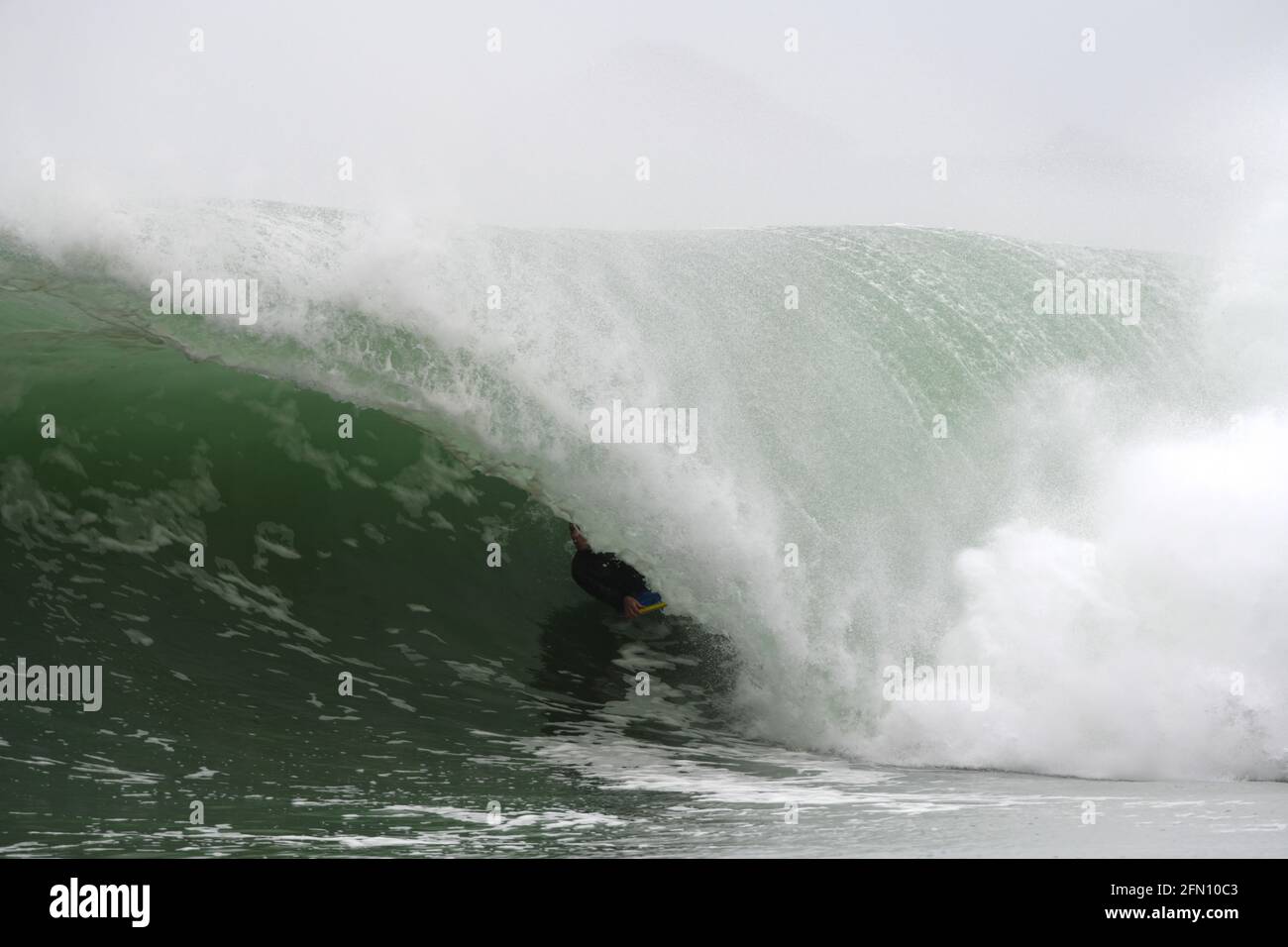 Surfing in Cornwall. A bodyboarder rides deep inside the tube of a ...