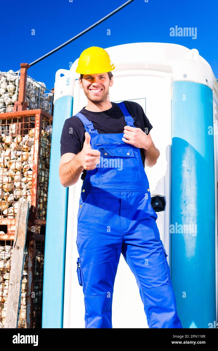 builder using mobile restroom or chemical toilet on construction or ...