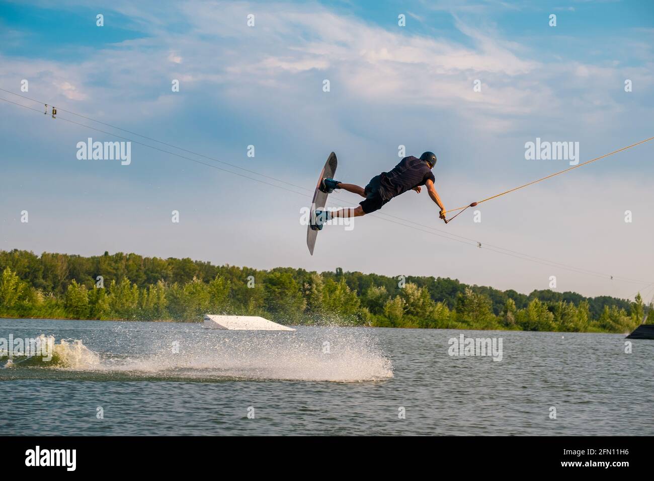 Male wakeboarder performing jump over water during summer training ...