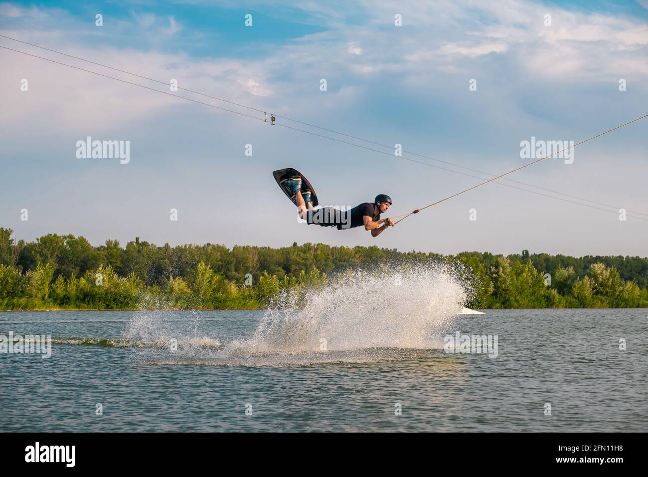 Male wakeboarder performing jumping over water creating splashes Stock ...