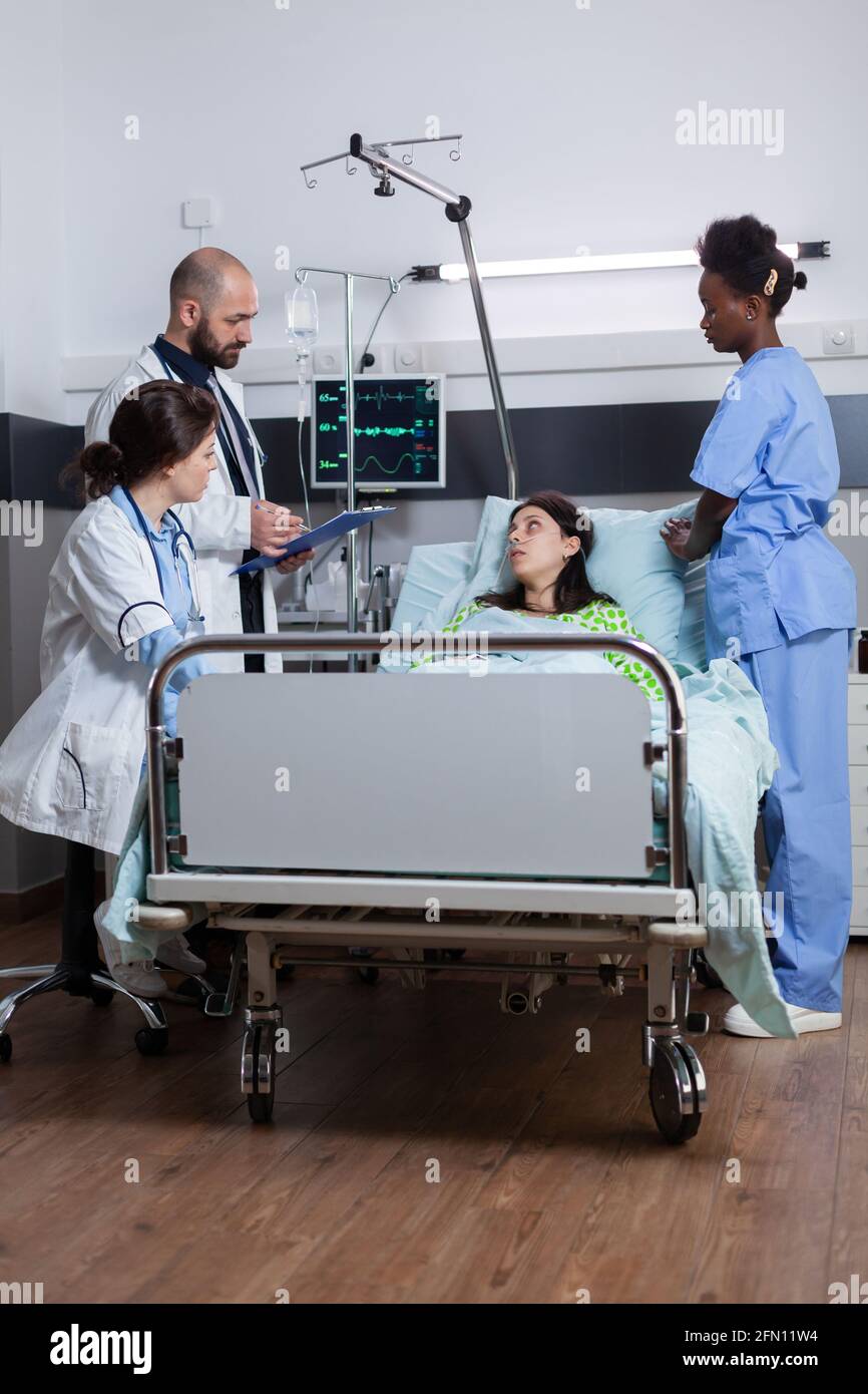 Practitioners doctors checking sick woman writing disease treatment on ...