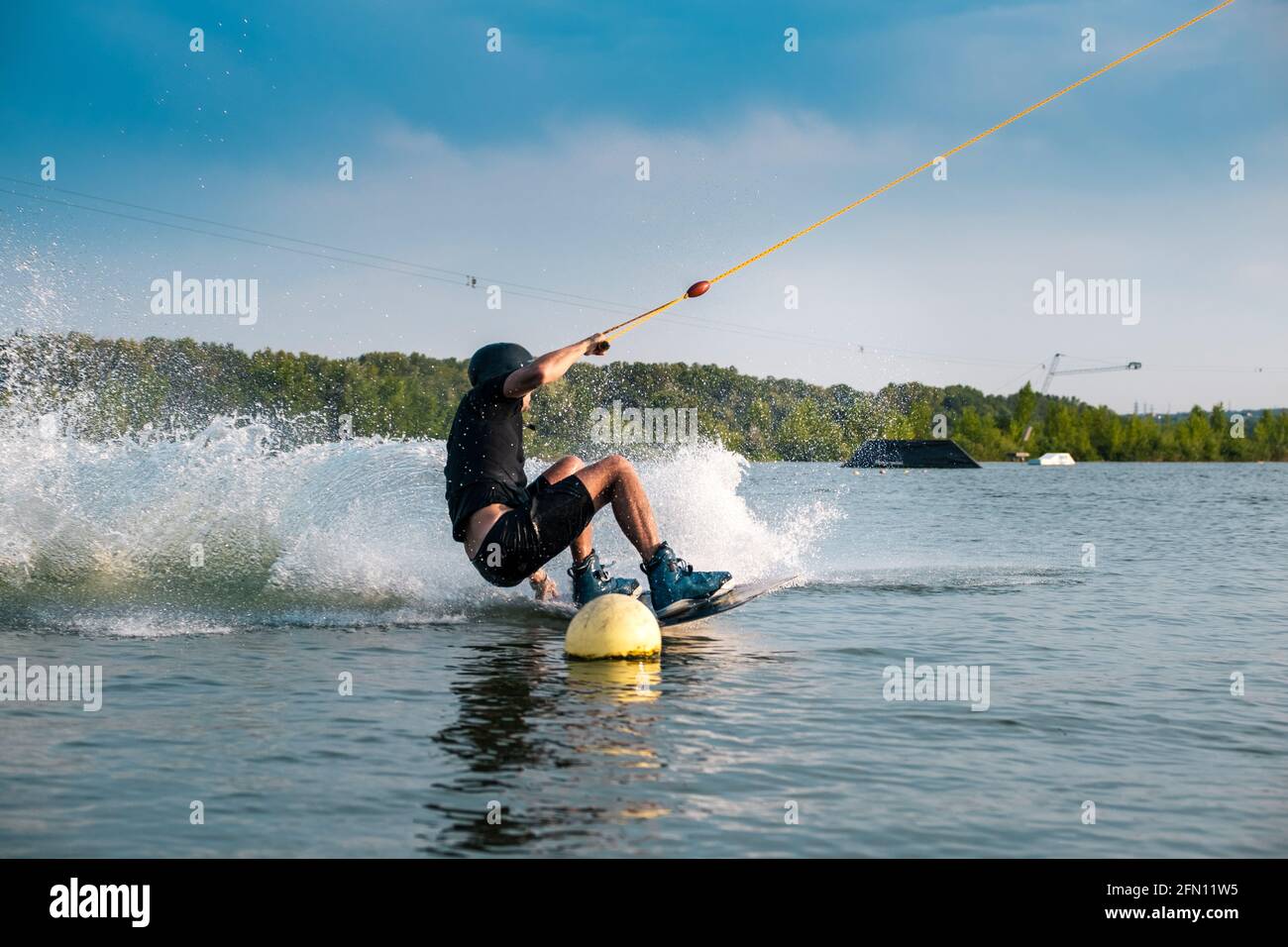 Wakeboarder making grab of board maneuvering between buoys Stock Photo ...
