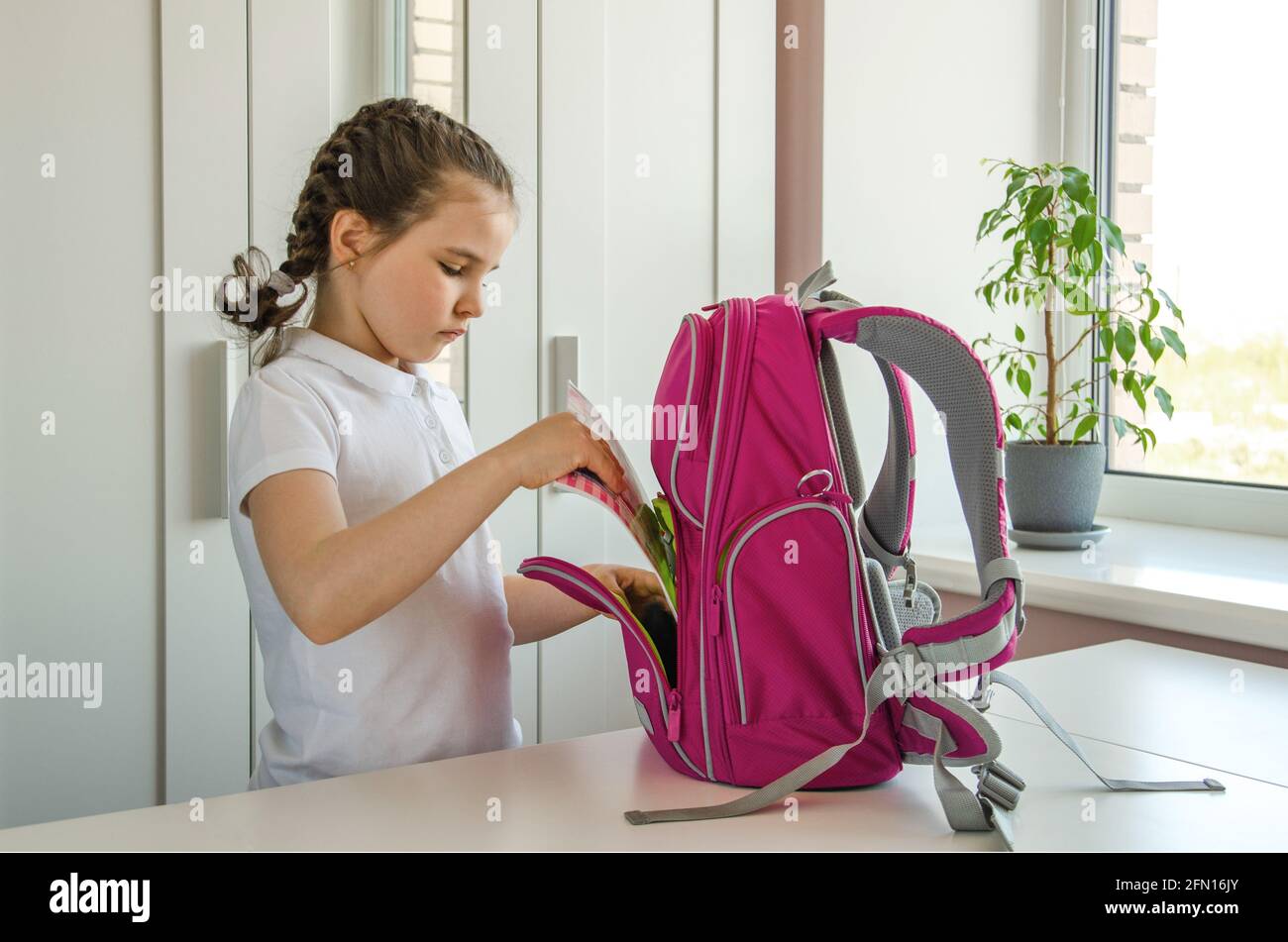 Schoolgirl in school clothes preparing for school and collecting ...
