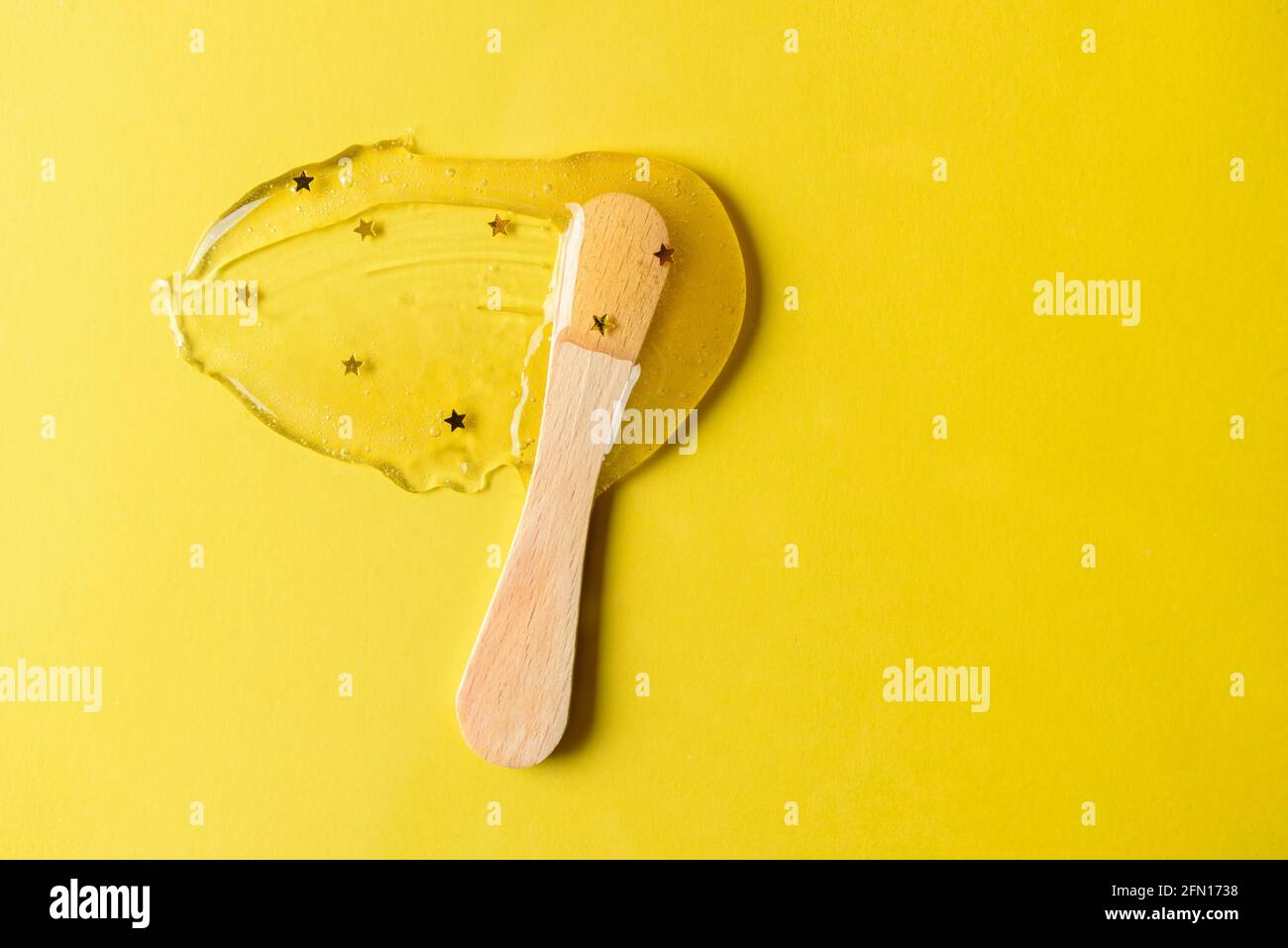 Liquid sugar wax glitter smear with spatula on yellow background Stock ...