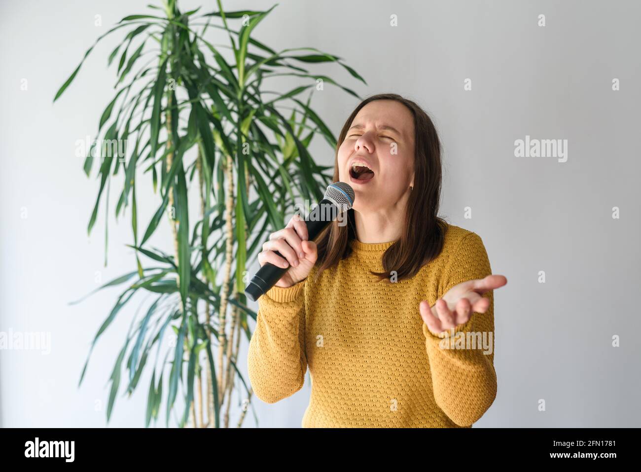 Woman singing with microphone at home with expression Stock Photo - Alamy