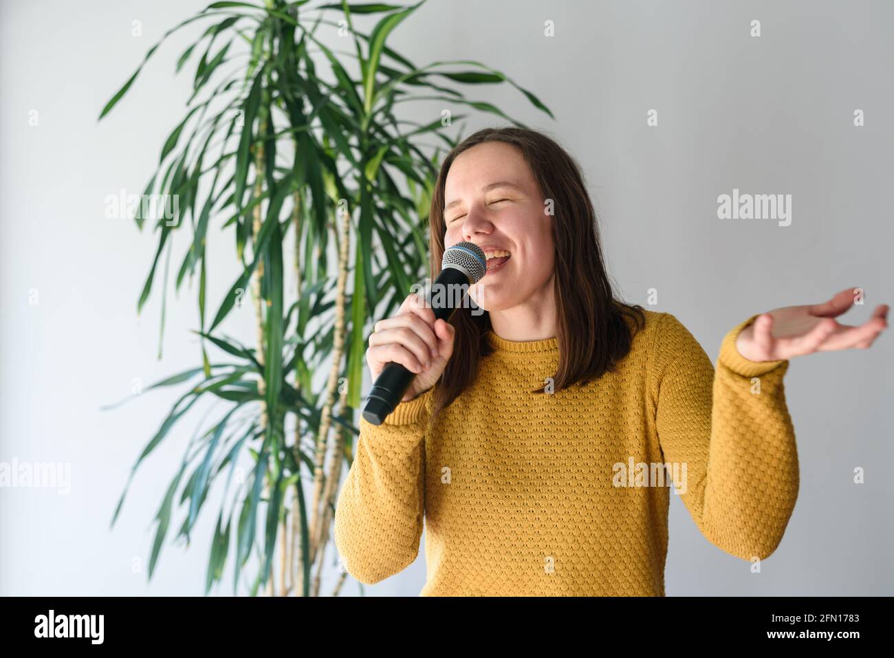 Woman singing with microphone at home with expression Stock Photo - Alamy
