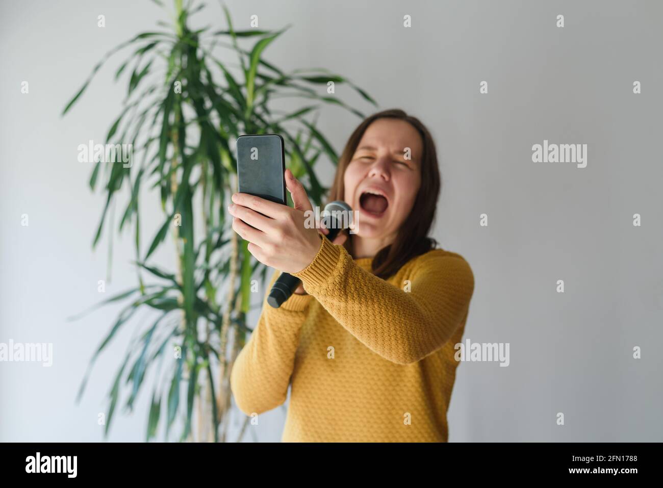 Woman blogger singing with microphone at home with expression. Taking ...