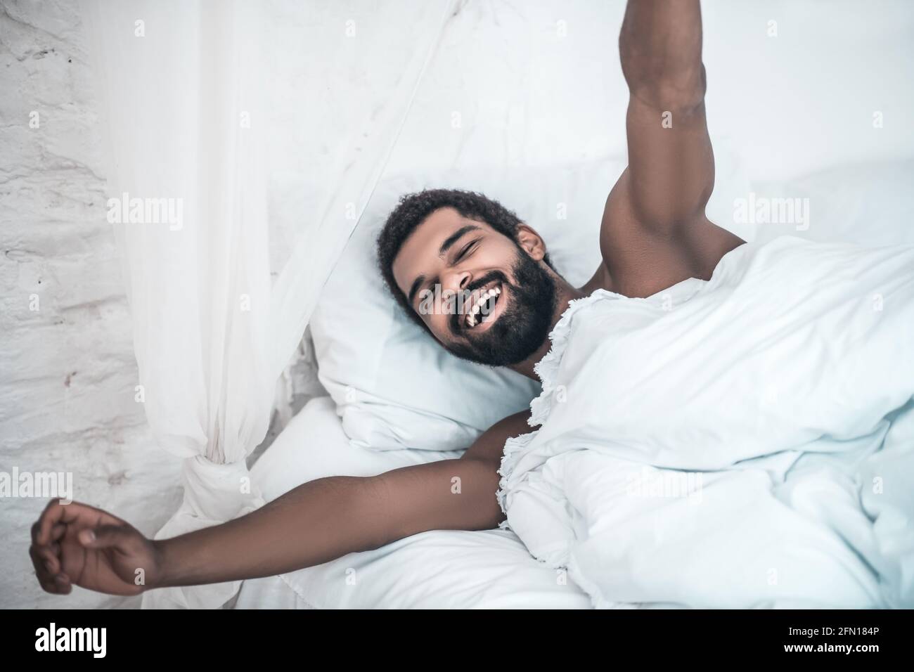 Joyful waking man stretching in bed Stock Photo - Alamy