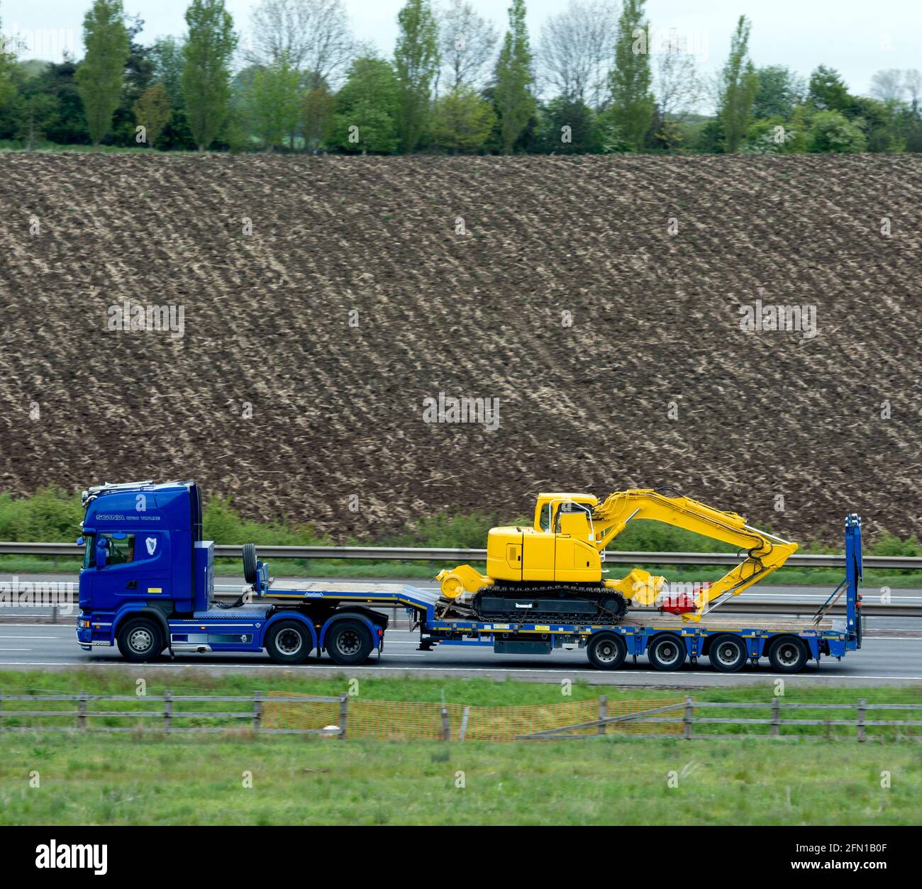 A low-loader articulated lorry carrying a digger, M40 motorway ...
