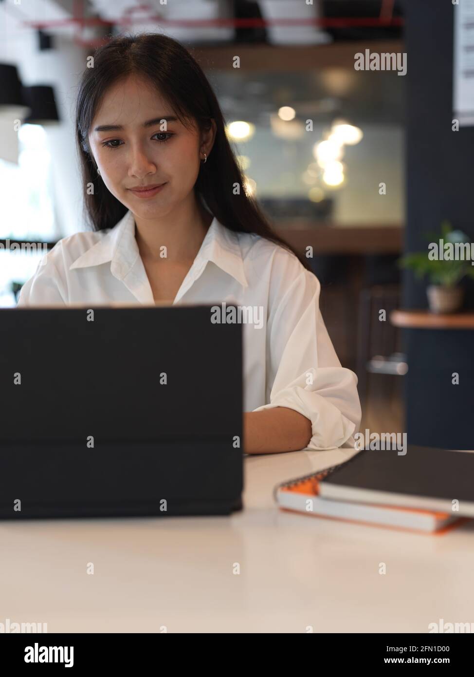 Portrait of female office worker working with laptop on worktable with ...
