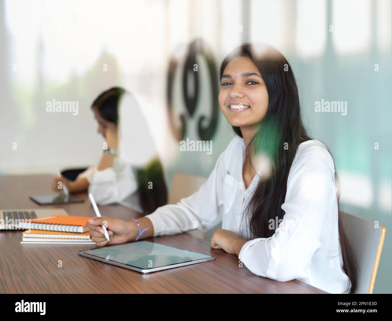 View through glass window of female university student smiling and ...