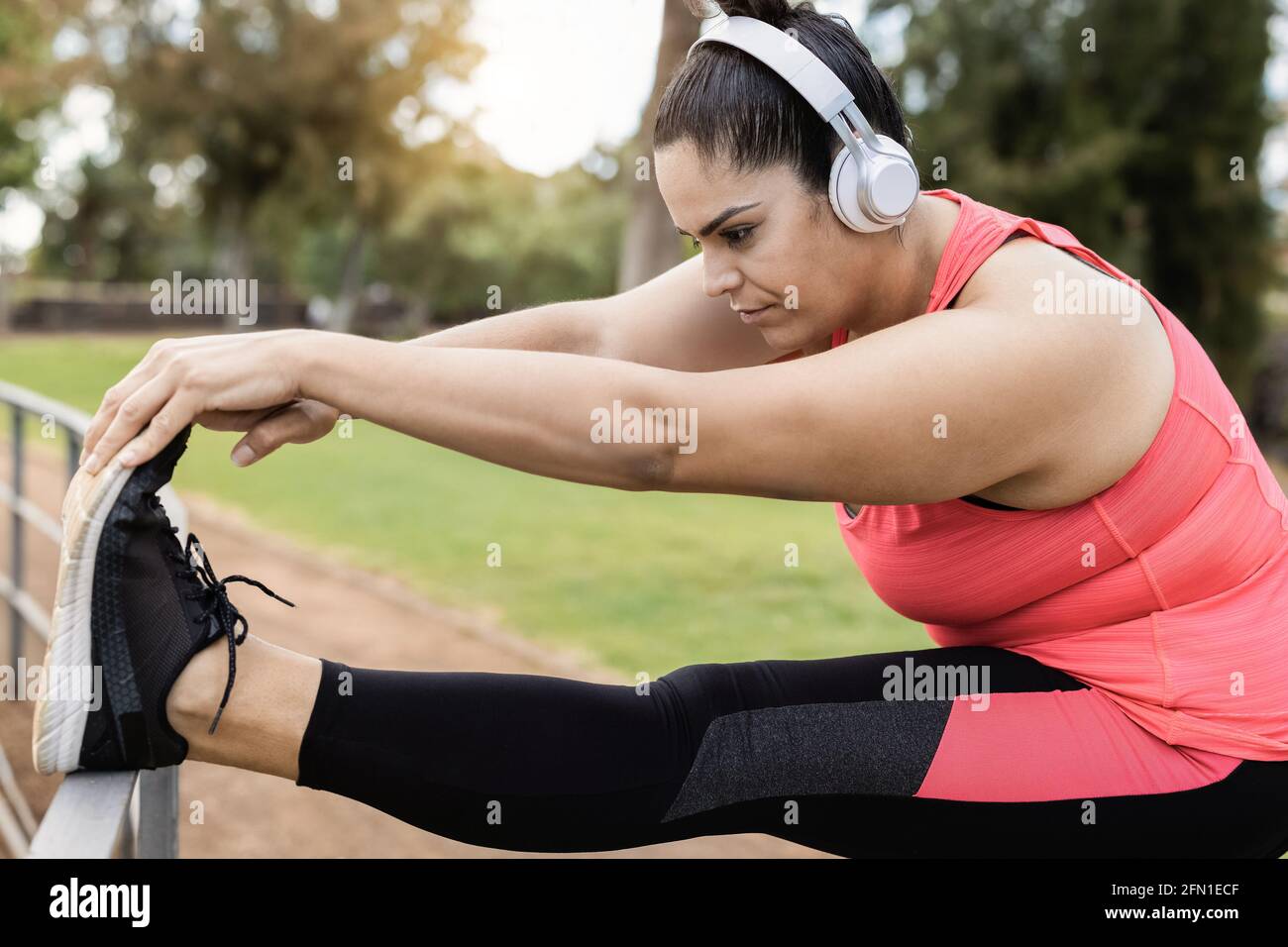 Plus size woman doing stretching day routine outdoor at city park ...