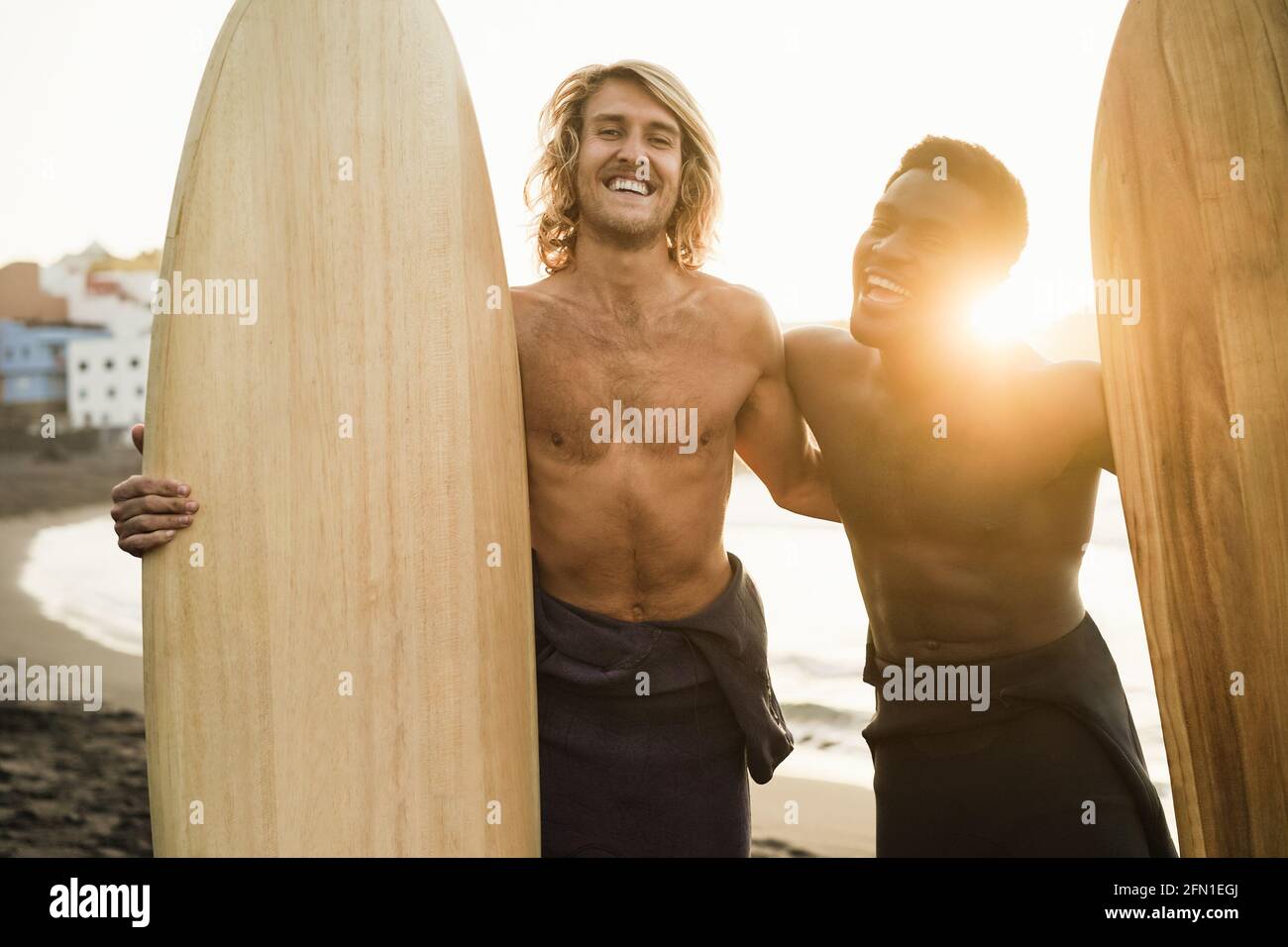 Happy multiracial surfers having fun on the beach after surf session ...