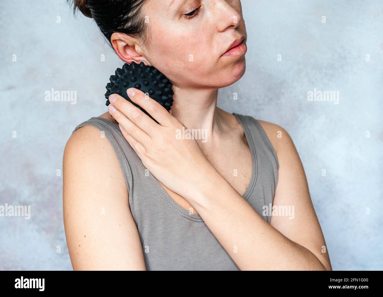 A woman massages her back with spiky trigger point ball, muscle pain ...