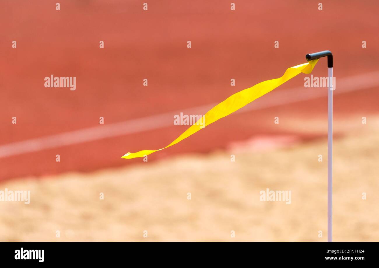Yellow wind flag on track and field stadium background. Long jump and ...