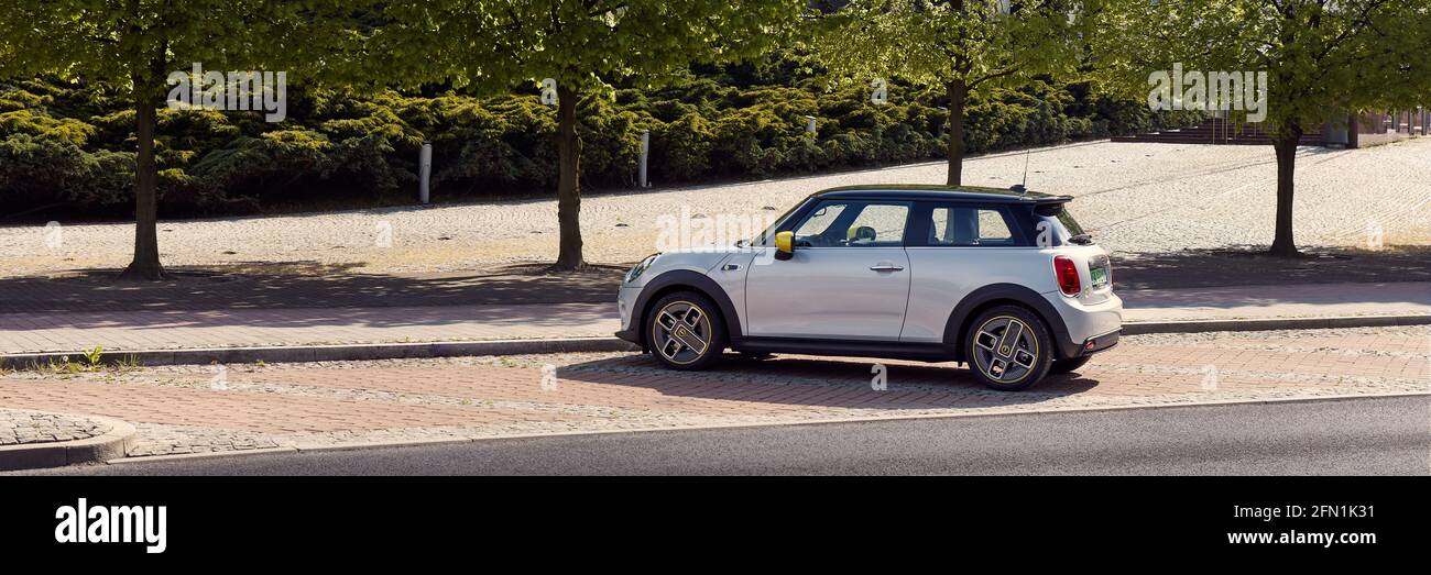 First fully electric Mini parked in the street under the trees. The ...