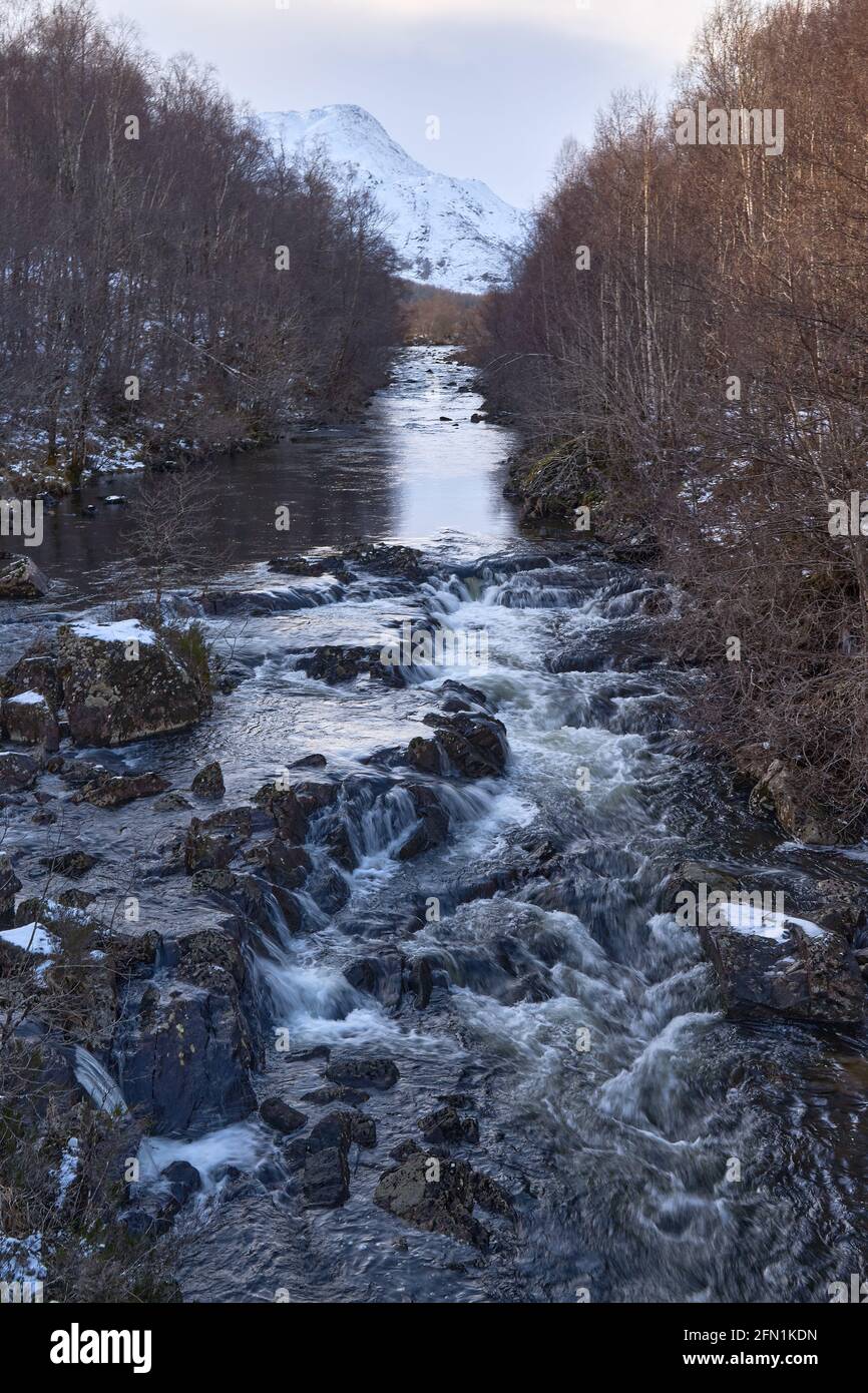 mighty river in a forest with snowy mountains in winter in Scotland, Uk ...