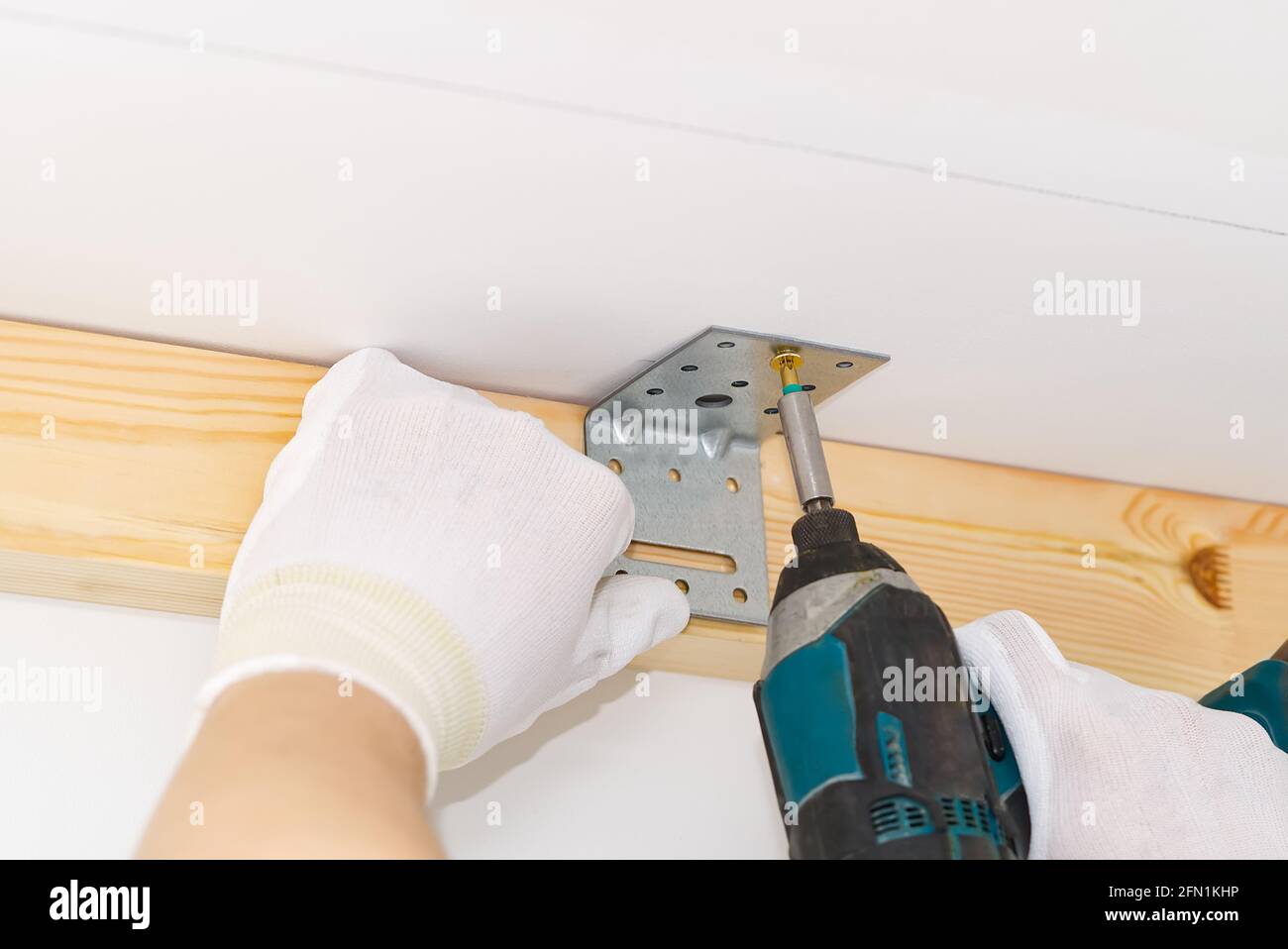 the master screws the metal corner to the concrete ceiling using a ...