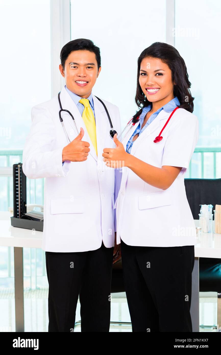 Asian male and female doctor standing proud in his office or medical ...
