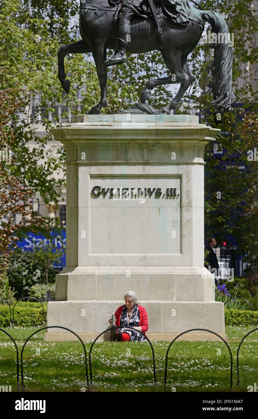 London, England, UK. Woman relaxing with a flask of tea by the statue ...