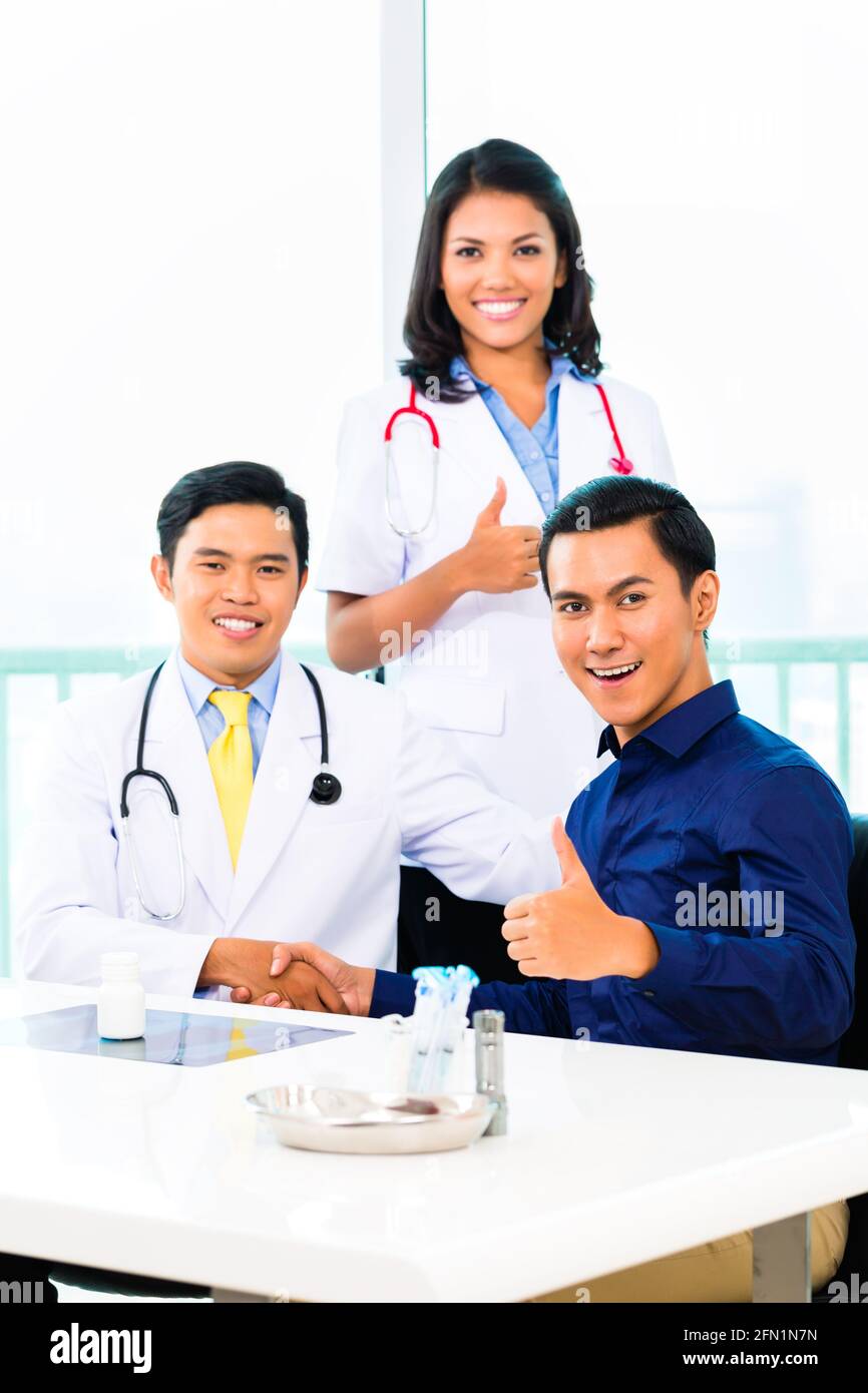 Asian doctor giving patient handshake for complete healing in practice ...